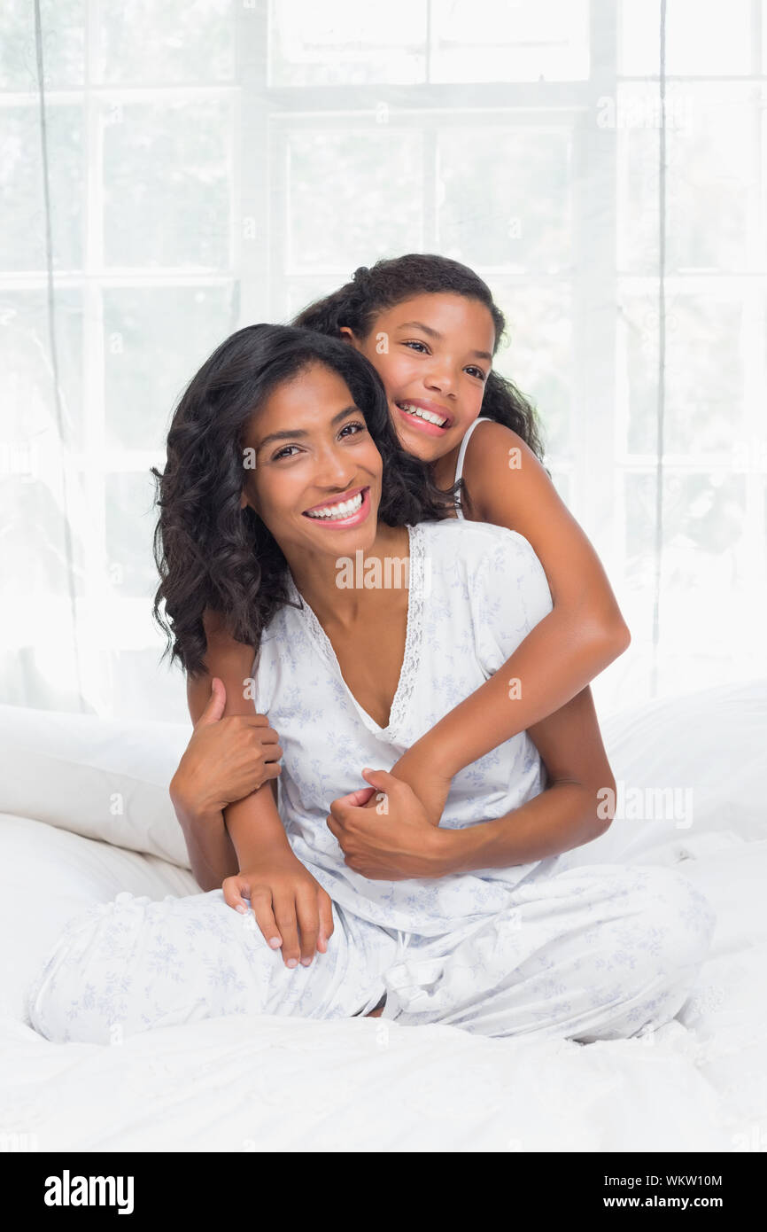 Smiling mother and daughter posing together on bed at home in bedroom Stock Photo - Alamy