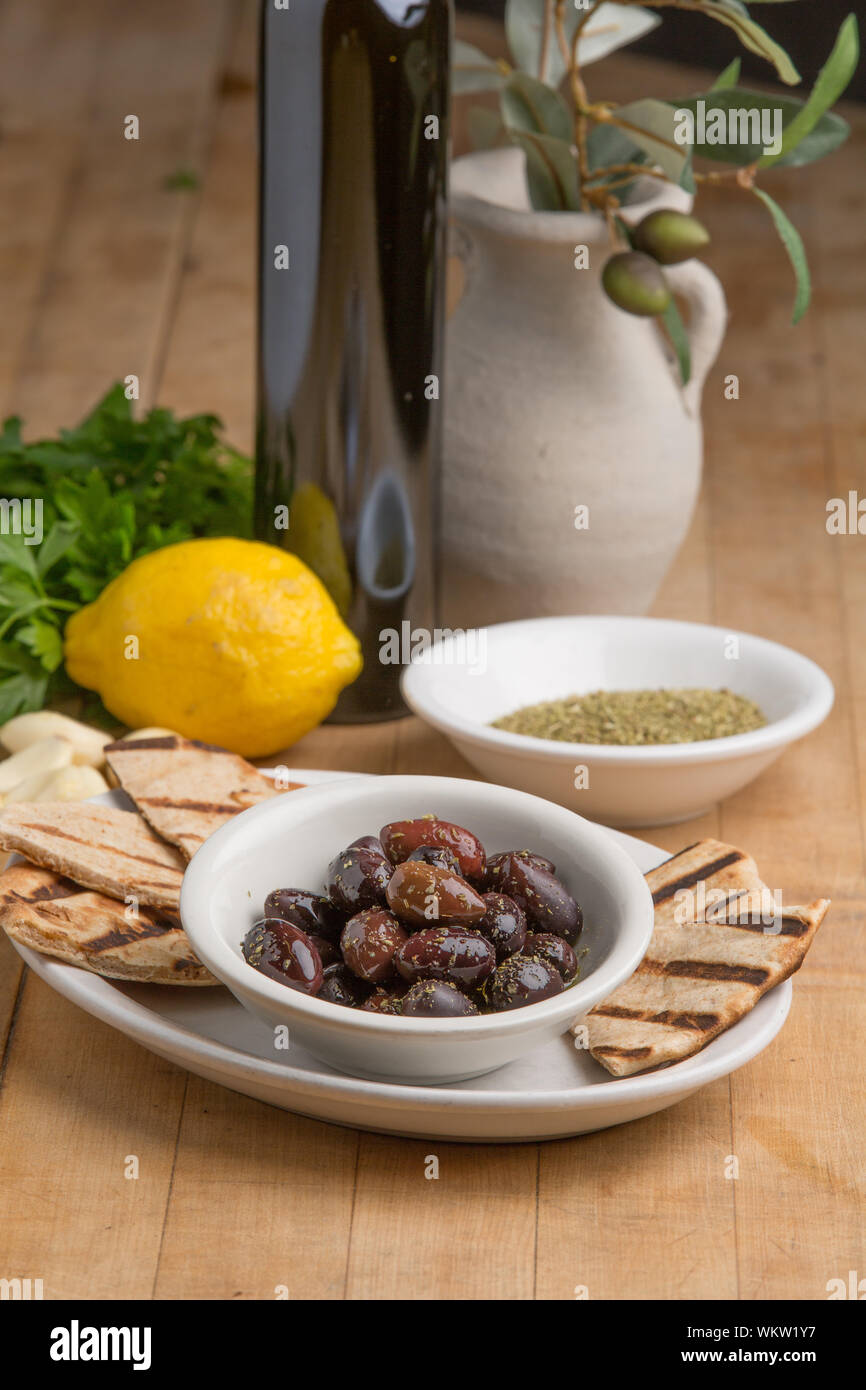 greek appetizers with olives and dips served on white plates with pita ...