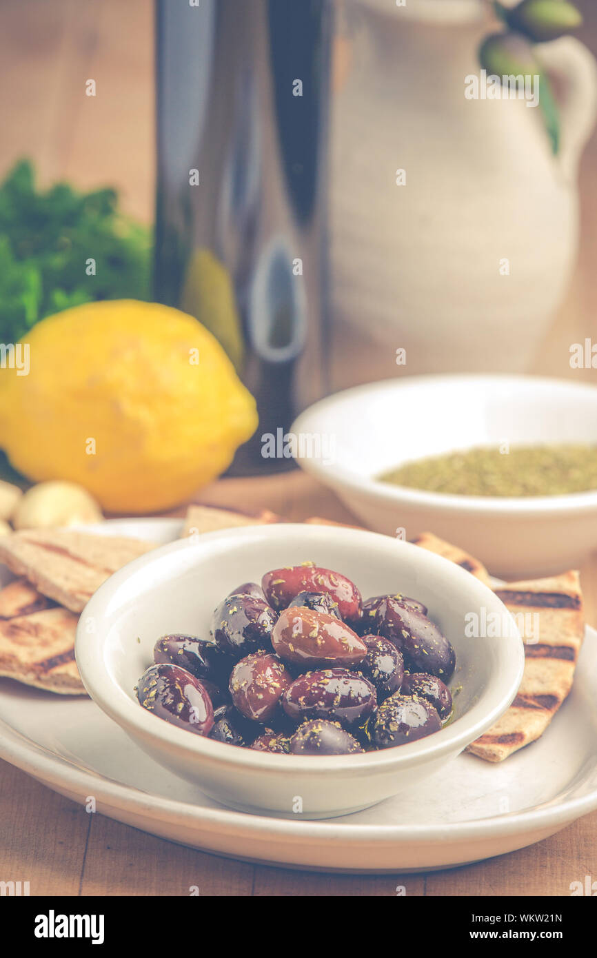 greek appetizers with olives and dips served on white plates with pita ...