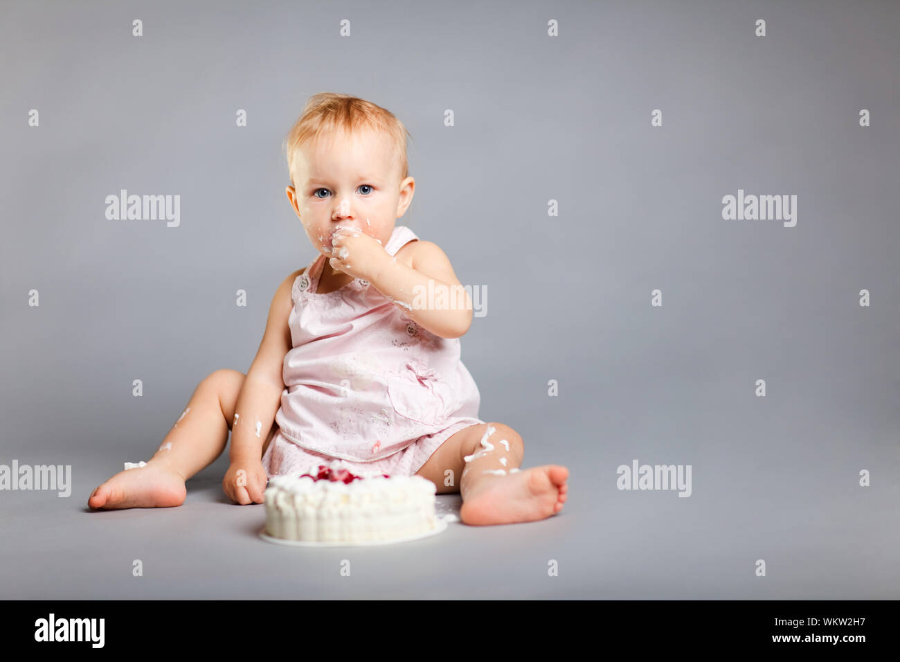 Cute little girl eating her first birthday cake Stock Photo - Alamy