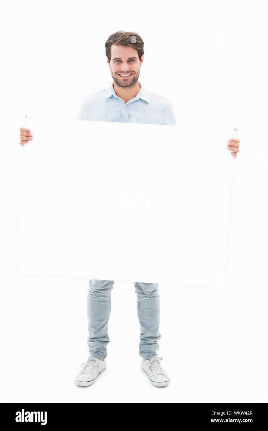 Attractive young man smiling and holding poster on white background ...