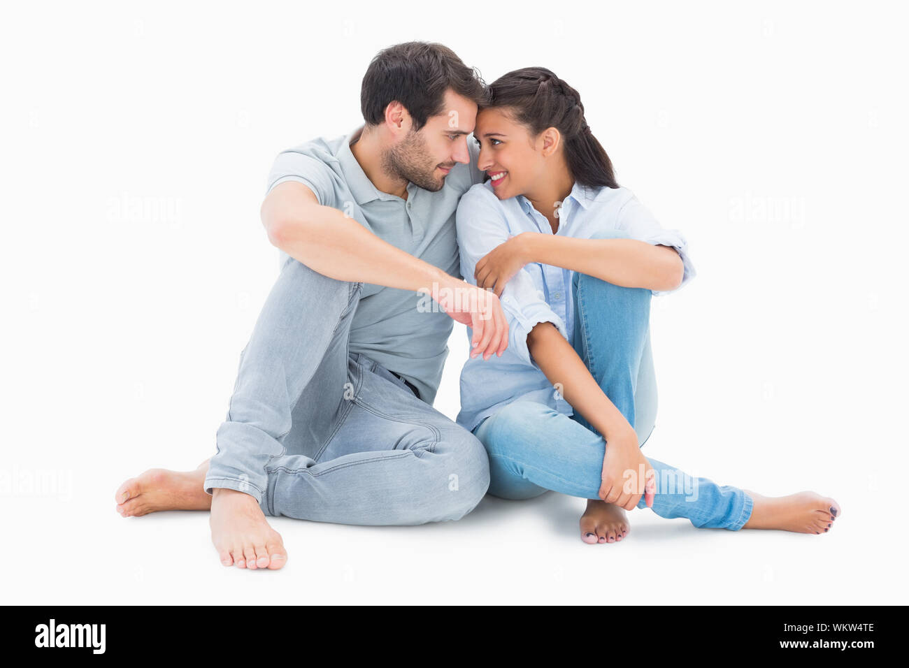 Cute couple sitting close together on white background Stock Photo - Alamy