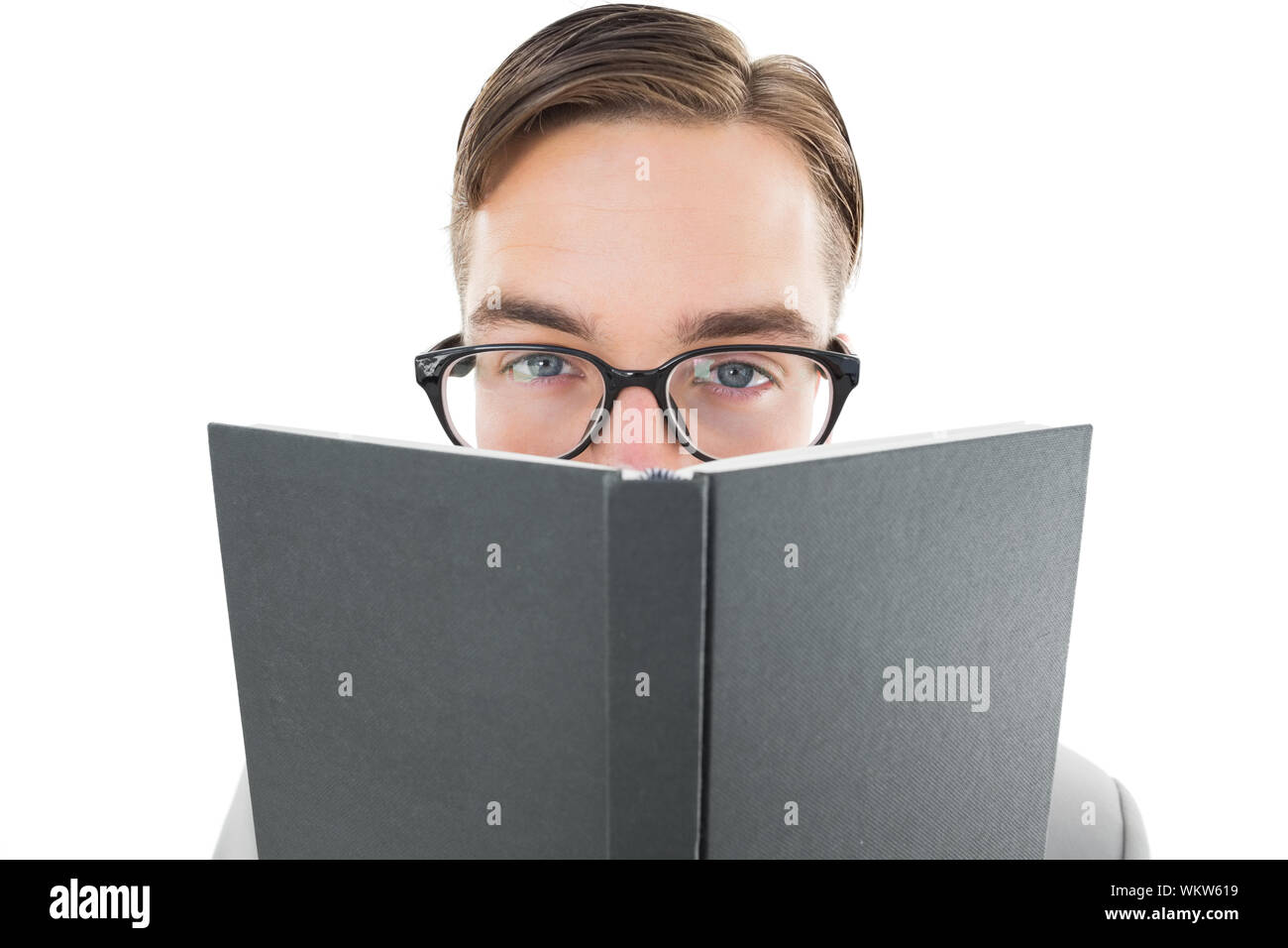 Geeky man looking over book on white background Stock Photo - Alamy
