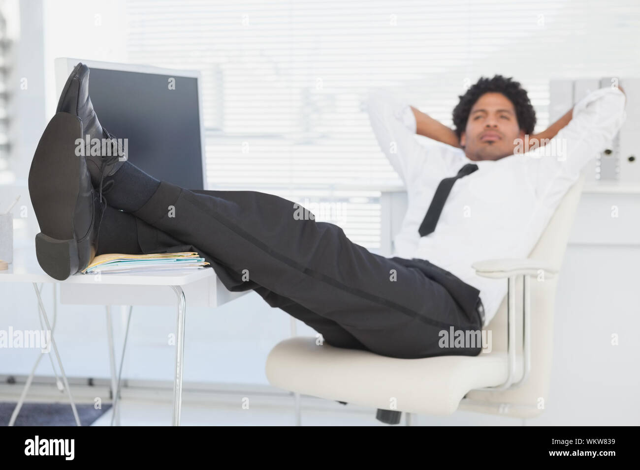 Businessman relaxing in his swivel chair with feet up in his office ...