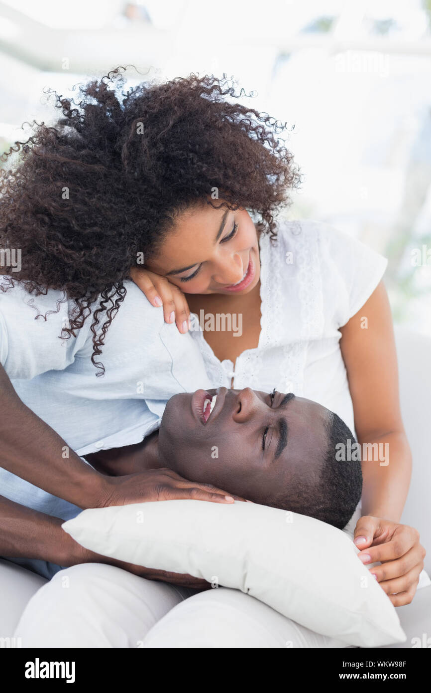 Attractive couple cuddling on the couch at home in the living room ...