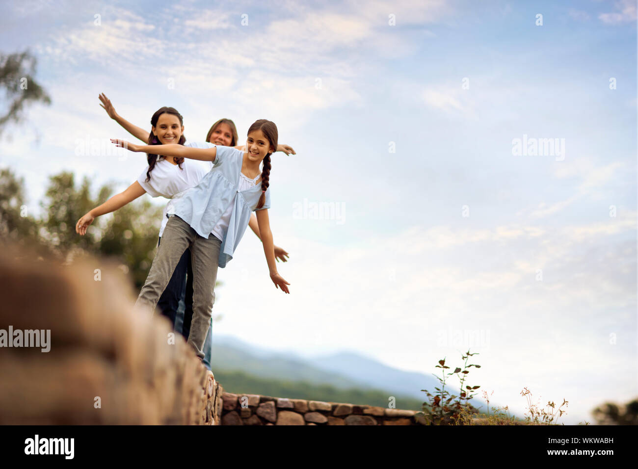Girl balancing while walking with her sister and mother Stock Photo - Alamy