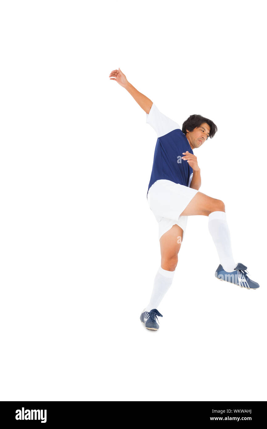 Football player in blue kicking on white background Stock Photo - Alamy