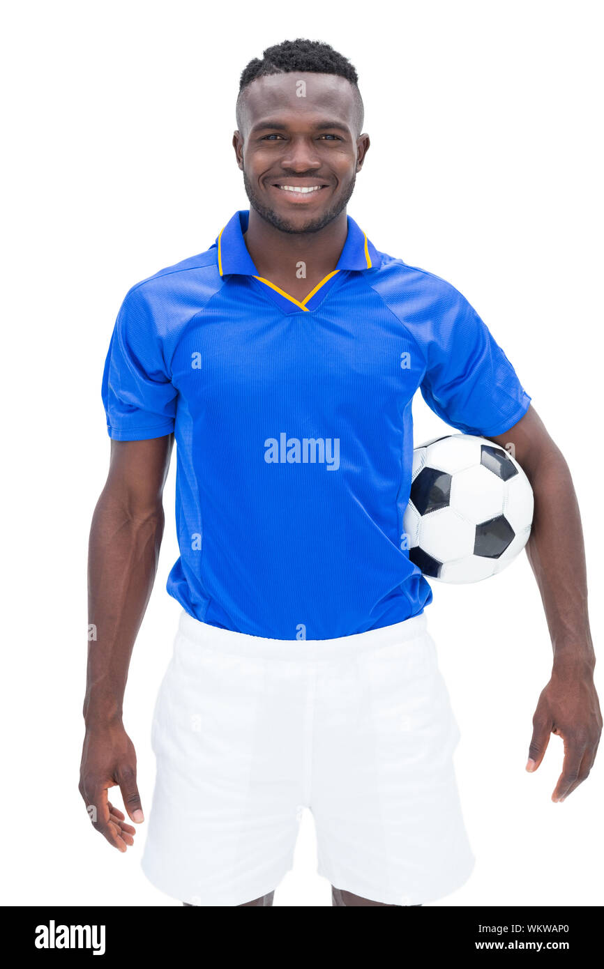 Football player in blue standing with the ball on white background ...
