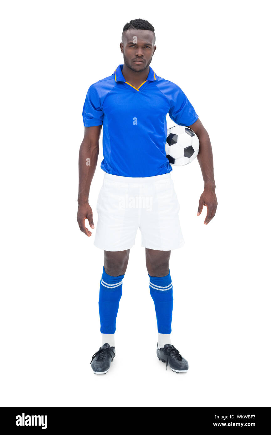 Football player in blue standing with the ball on white background ...