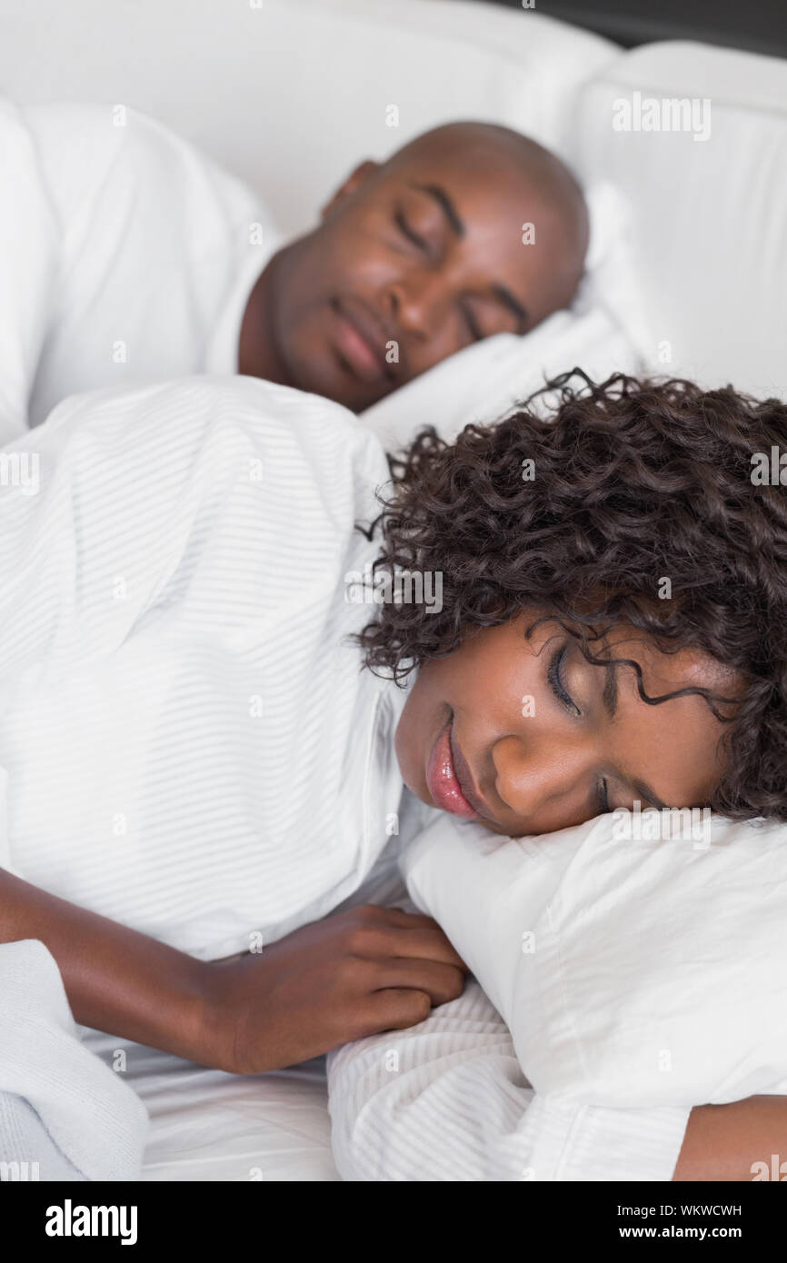Happy couple lying in bed together sleeping at home in the bedroom ...