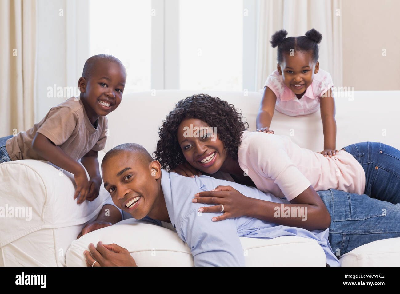 Happy family posing on the couch together at home in the living room ...