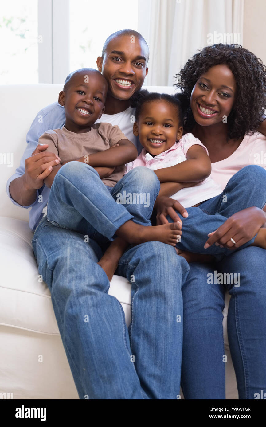 Happy family posing on the couch together at home in the living room ...
