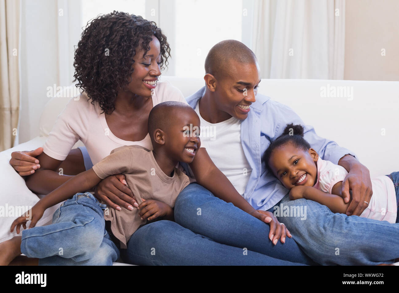 Happy family posing on the couch together at home in the living room ...