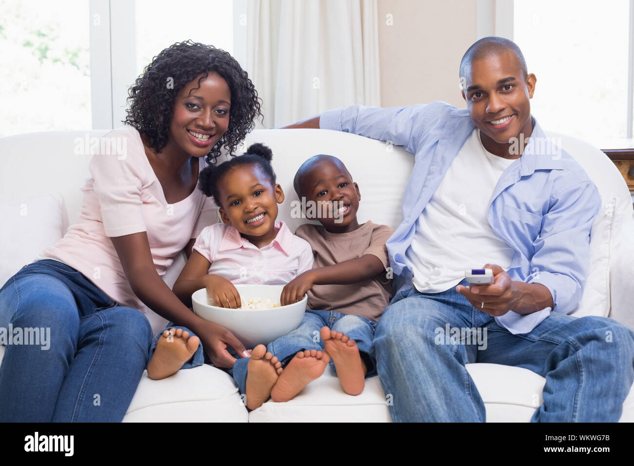 Happy family watching television together at home in the living room ...
