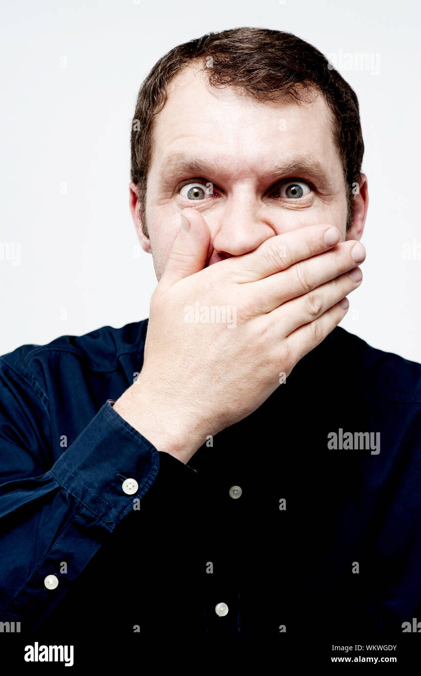 Middle aged scared man covering his mouth Stock Photo - Alamy