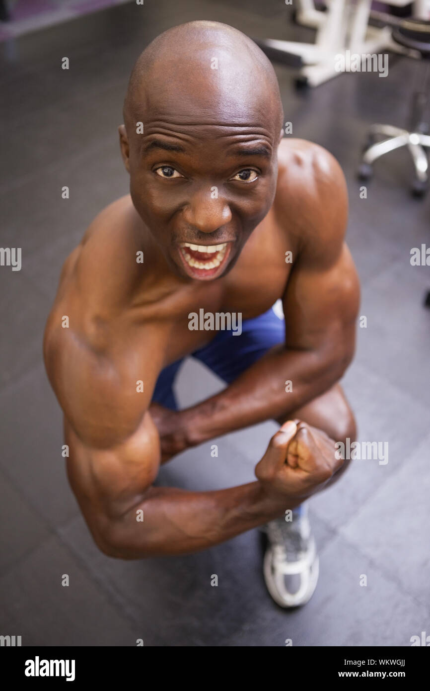 Portrait of a shirtless muscular man shouting while flexing muscles in ...