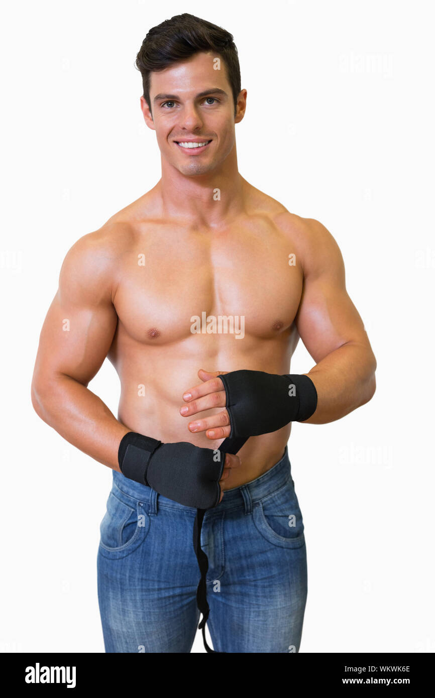 Shirtless muscular man binds bandage on his hand over white background ...