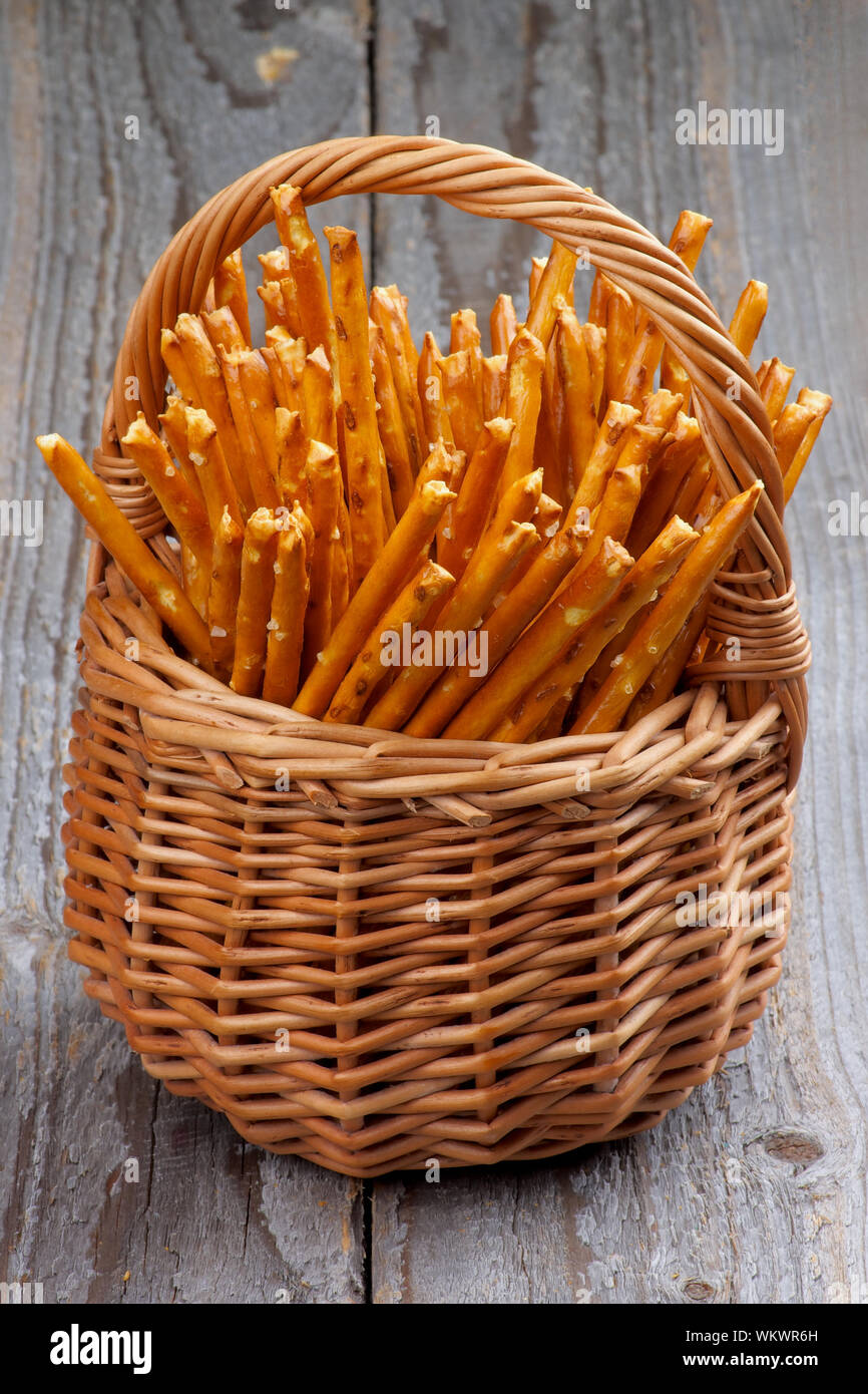 Bunch of Pretzel Rods Sticks in Wicker Basket isolated on Rustic Wooden ...