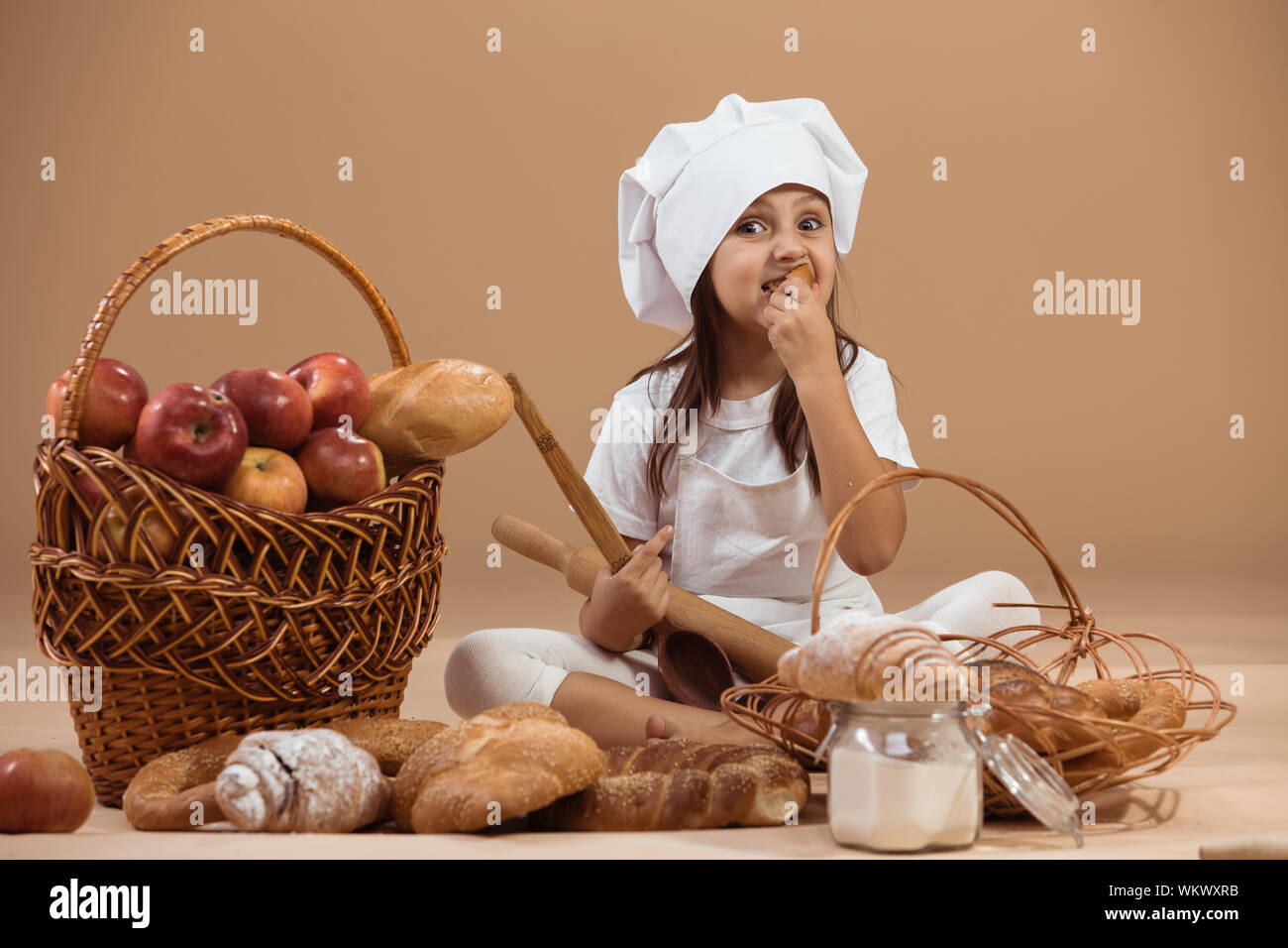 5 years old girl baker eating bakery products, studio shot Stock Photo ...