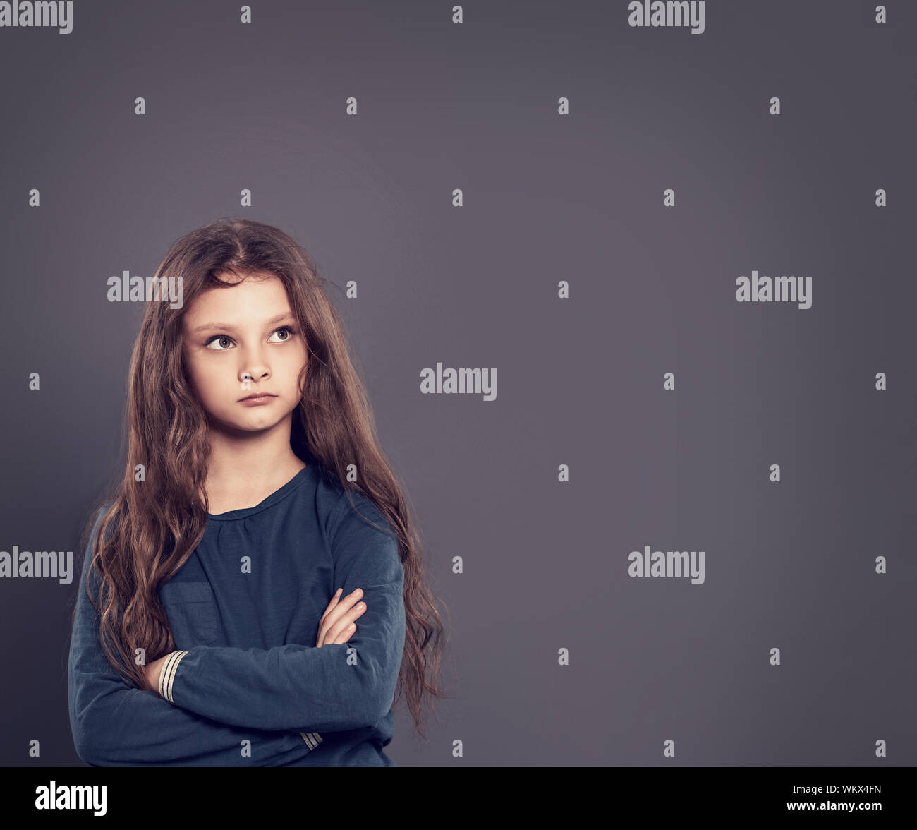 Thinking casual pupil kid girl with folded arms thinking and looking up ...