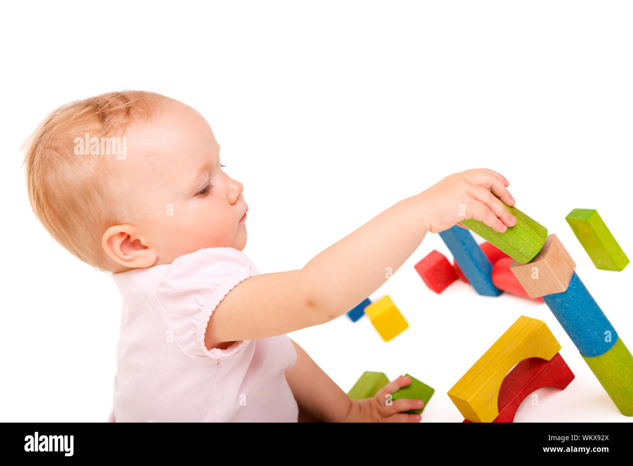 Cute baby girl building with colorful wooden blocks. Isolated on white ...