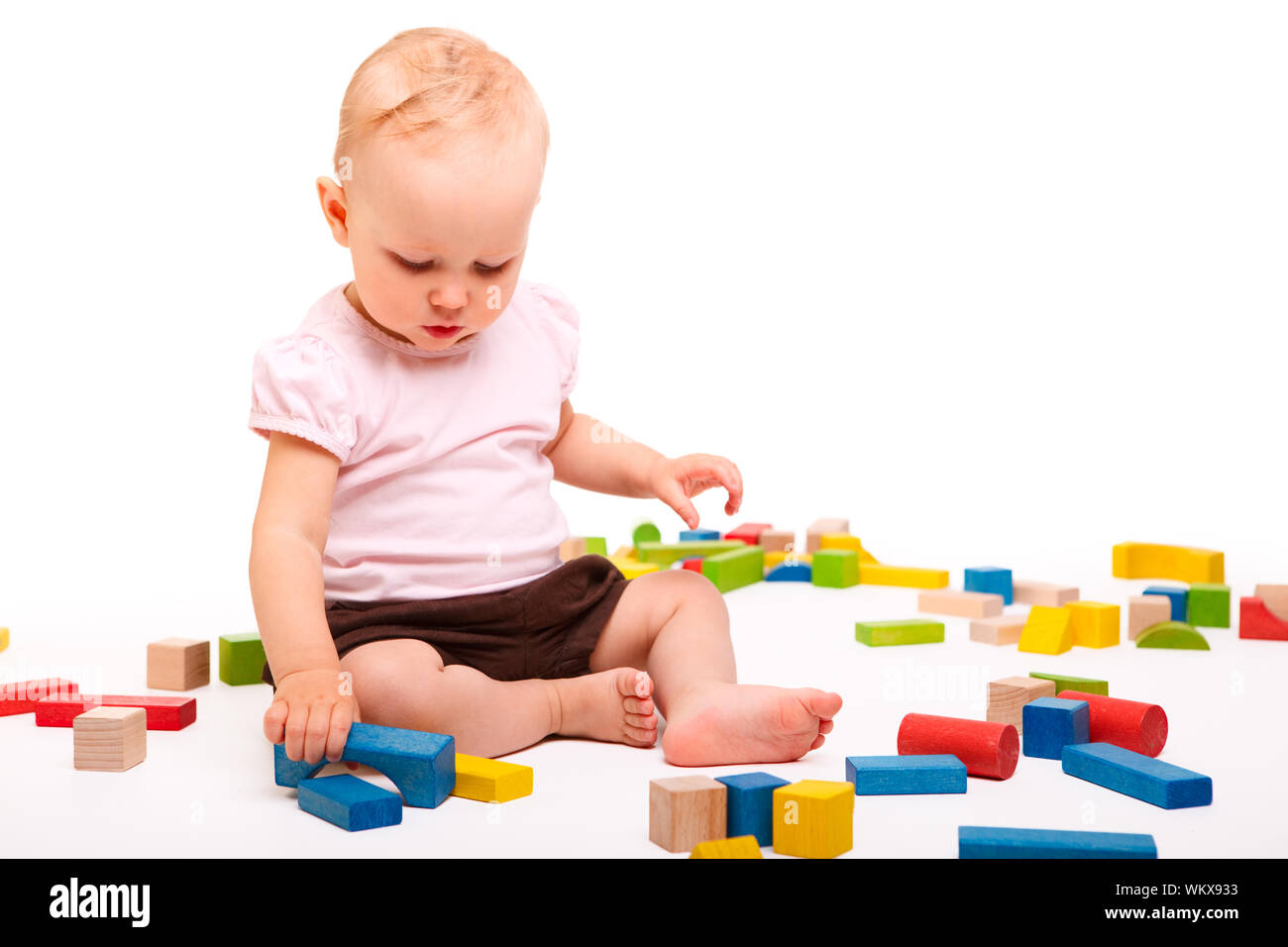 Cute baby girl building with colorful wooden blocks. Isolated on white ...