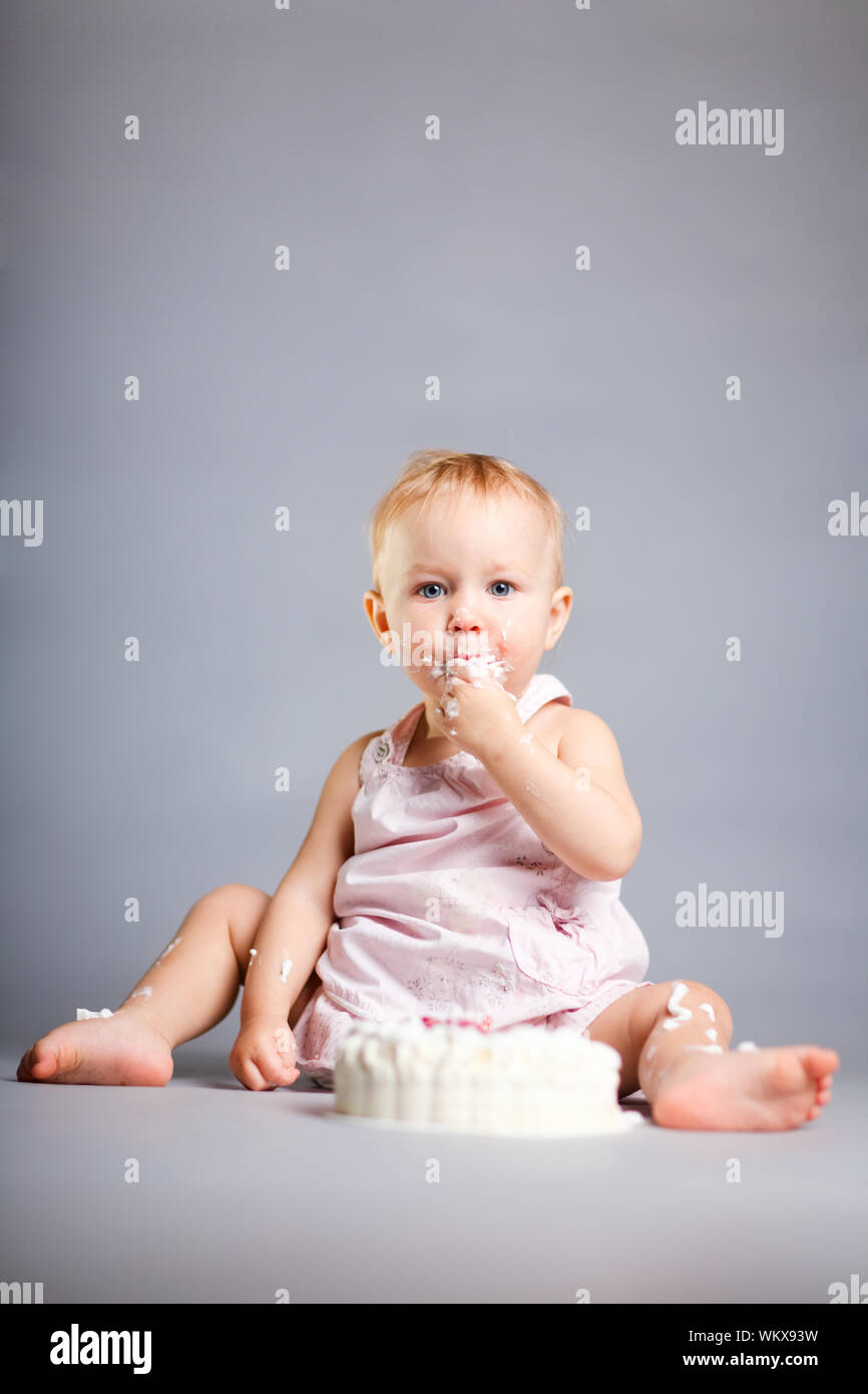 Cute little girl eating her first birthday cake Stock Photo - Alamy