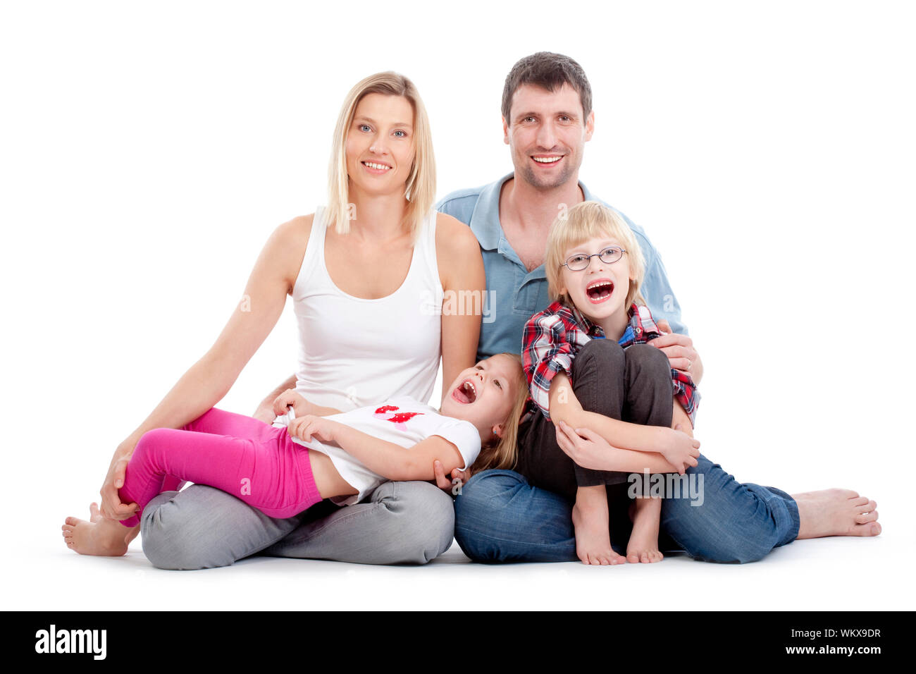 happy parents with their two children looking at the camera, smiling ...