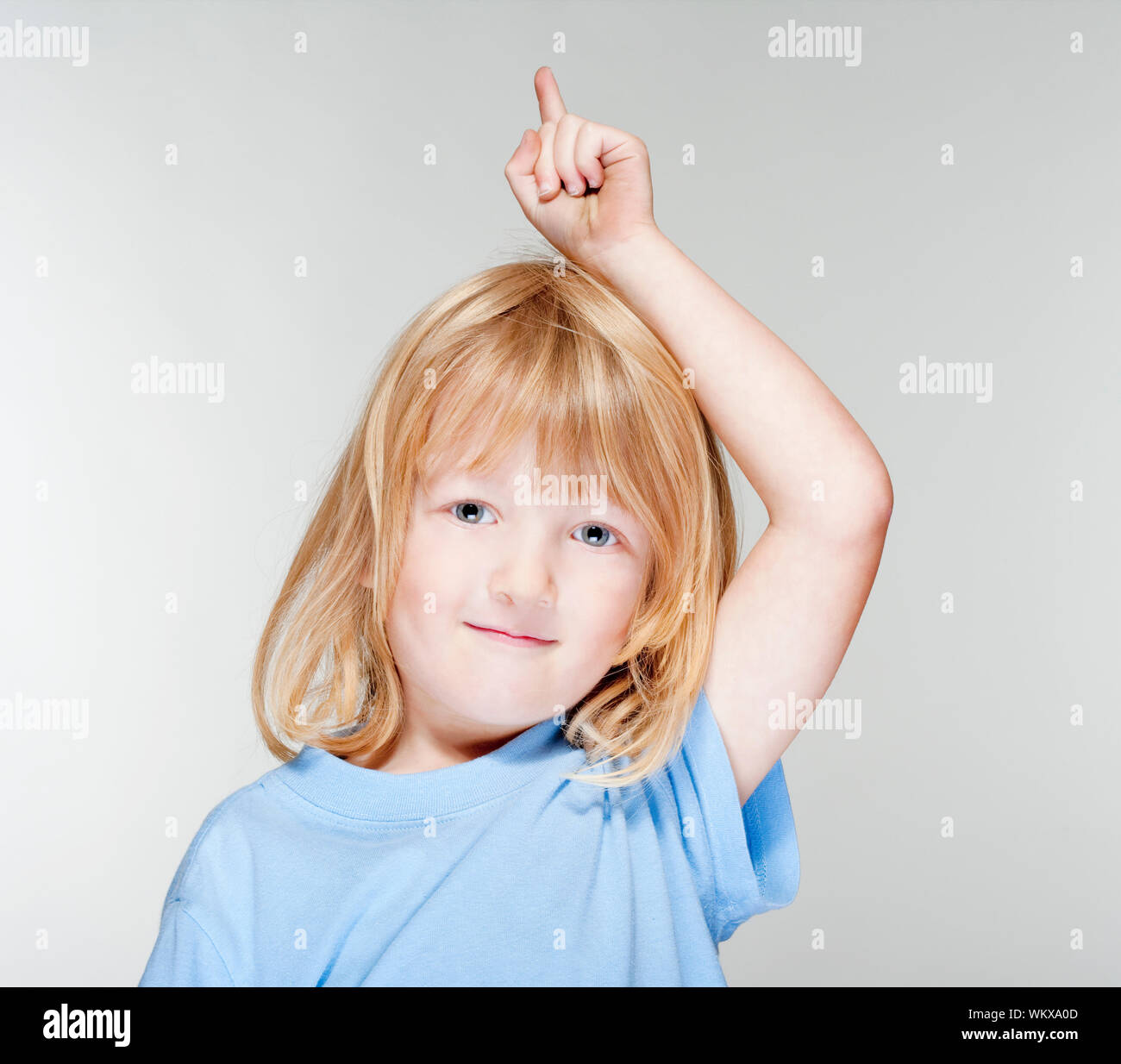 boy with long blond hair pointing up - isolated on gray Stock Photo - Alamy