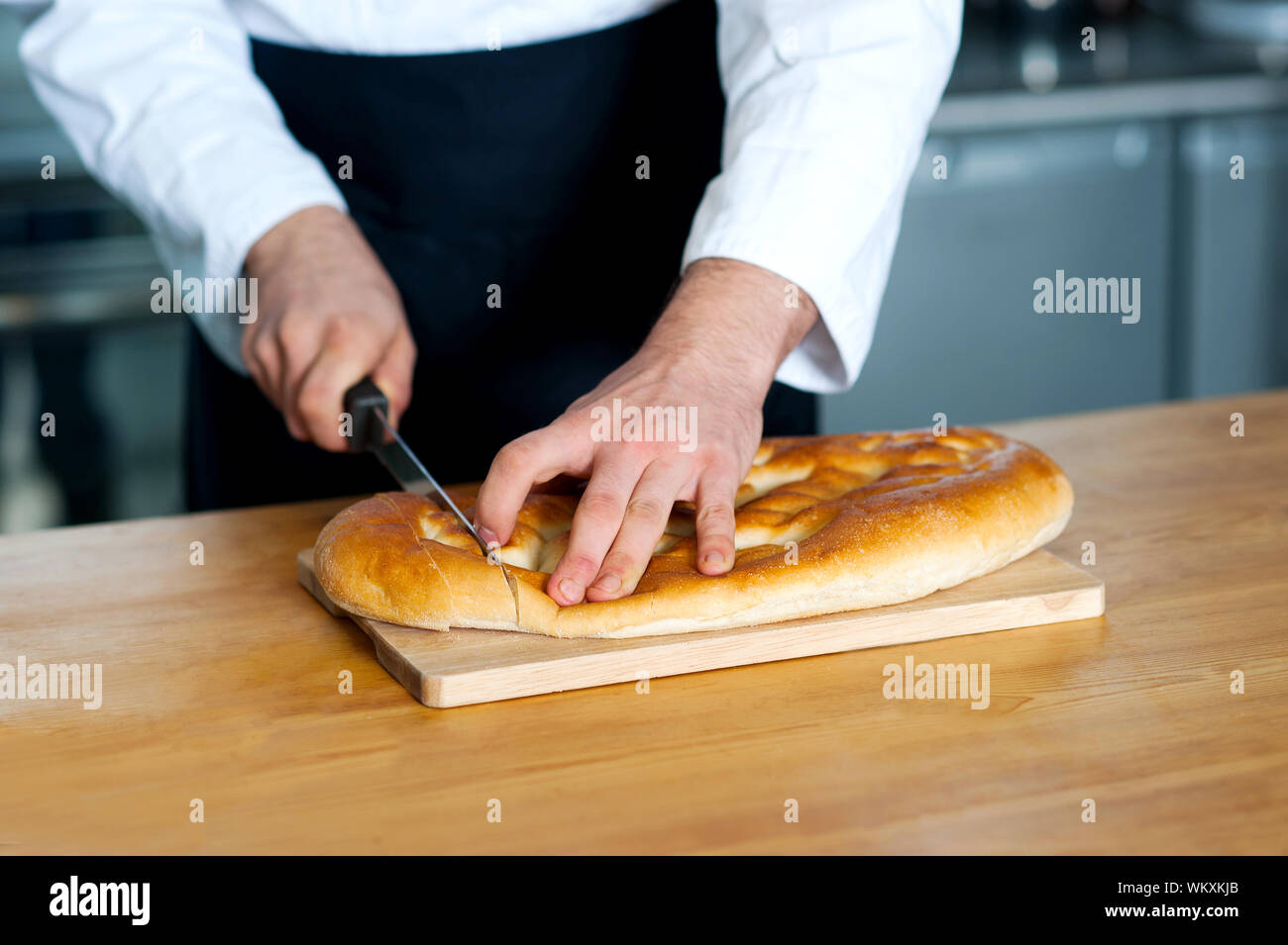 Hand with a knife sliced bread on a cutting board Stock Photo - Alamy