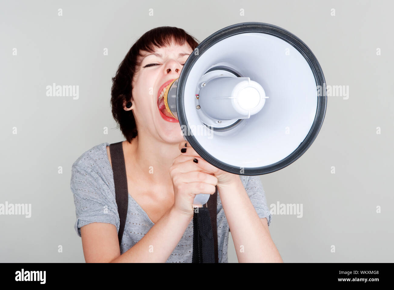 angry teenage girl yelling into a megaphone - isolated on gray Stock ...