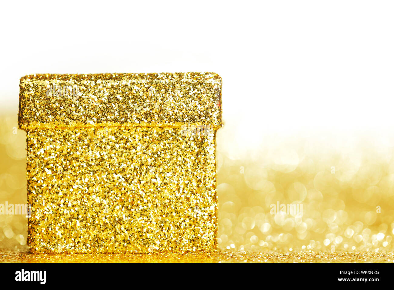 Decorative golden box with holiday gift on shiny glitter background ...