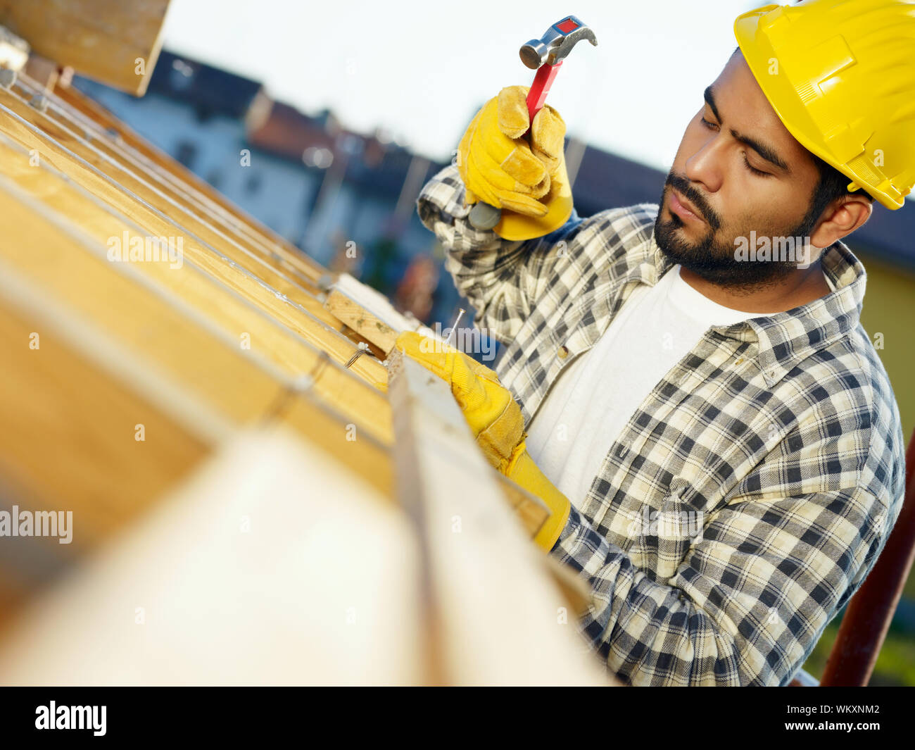 latin american construction worker on house roof with hammer. Copy ...