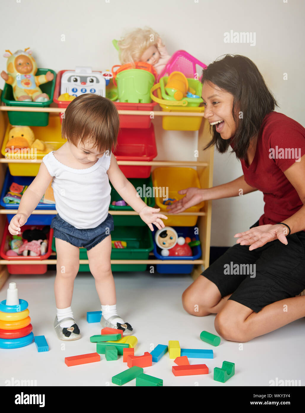 Baby sitter young girl playing with kid on toys background Stock Photo ...