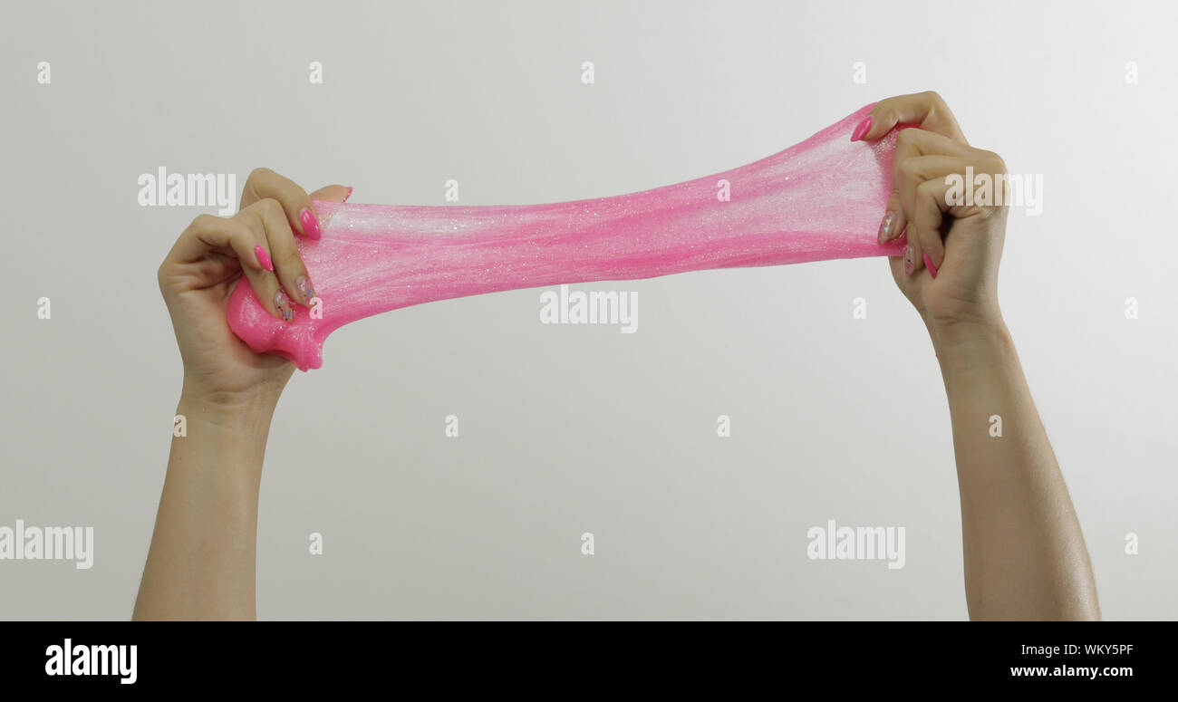 Woman hands playing with oddly satisfying pink slime on white ... Woman hands playing with oddly satisfying pink slime on white ...