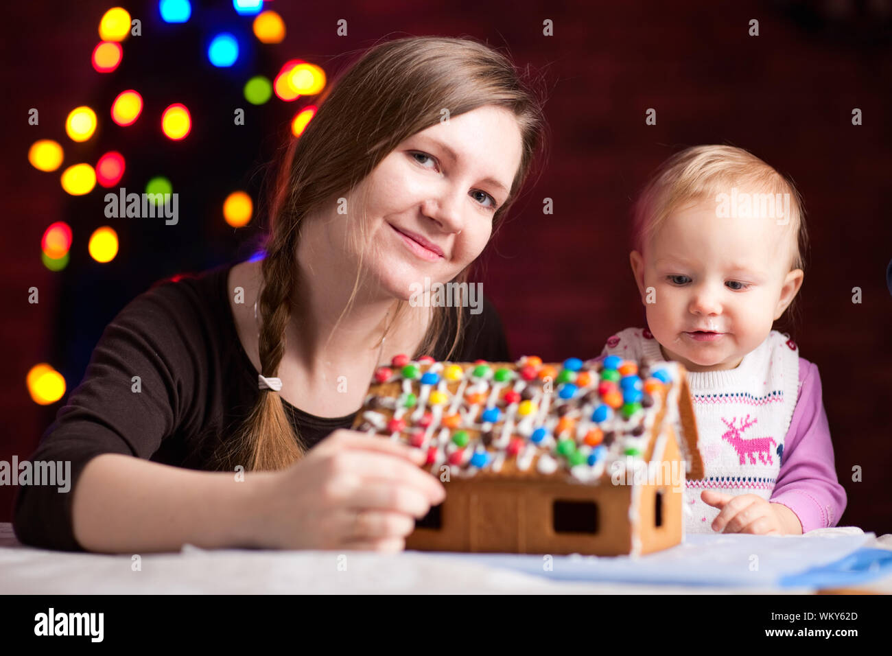 Family decorating gingerbread house at Christmas eve Stock Photo - Alamy