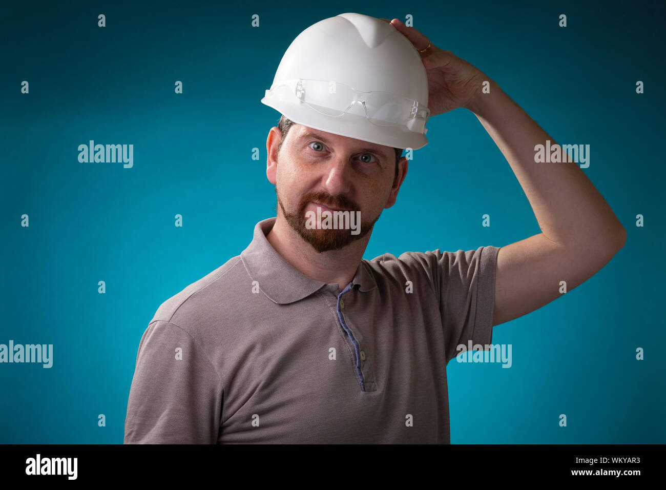 Construction worker with beard and white safety helmet looking into the ...
