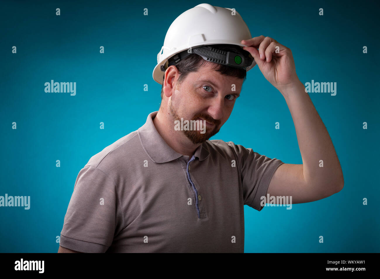 Foreman with beard holding a backwards placed white safety helmet ...
