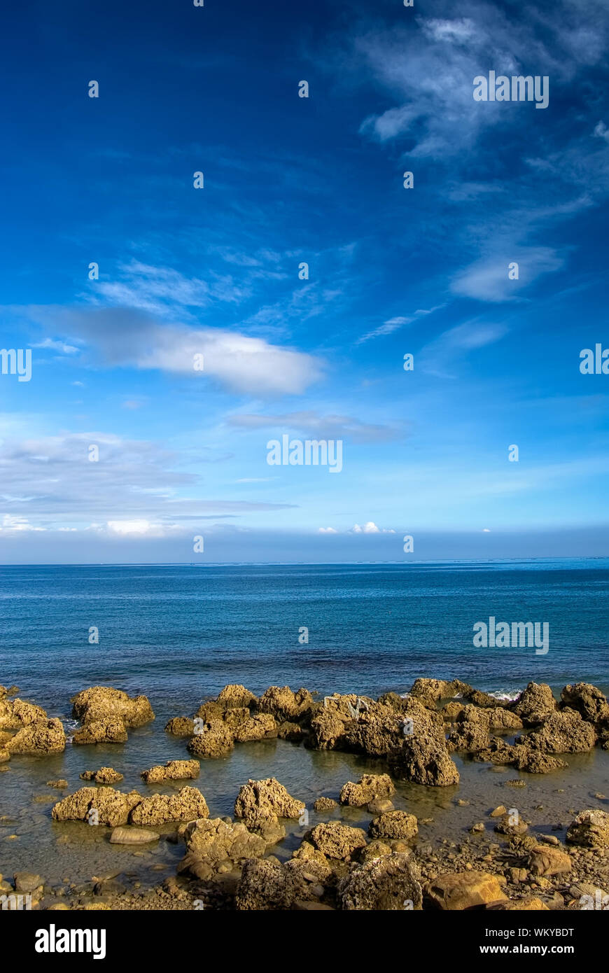 Landscape of golden coral reef rock coastline under blue sky and white ...
