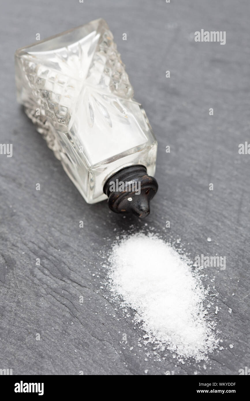 Salt shaker with spilt salt on a slate Stock Photo - Alamy