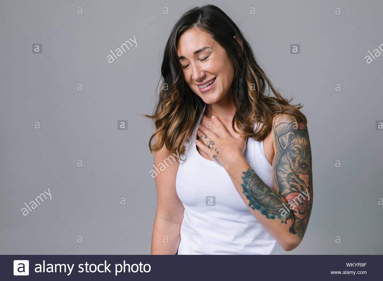 Portrait happy young woman with tattoos and hand over heart Stock Photo ...