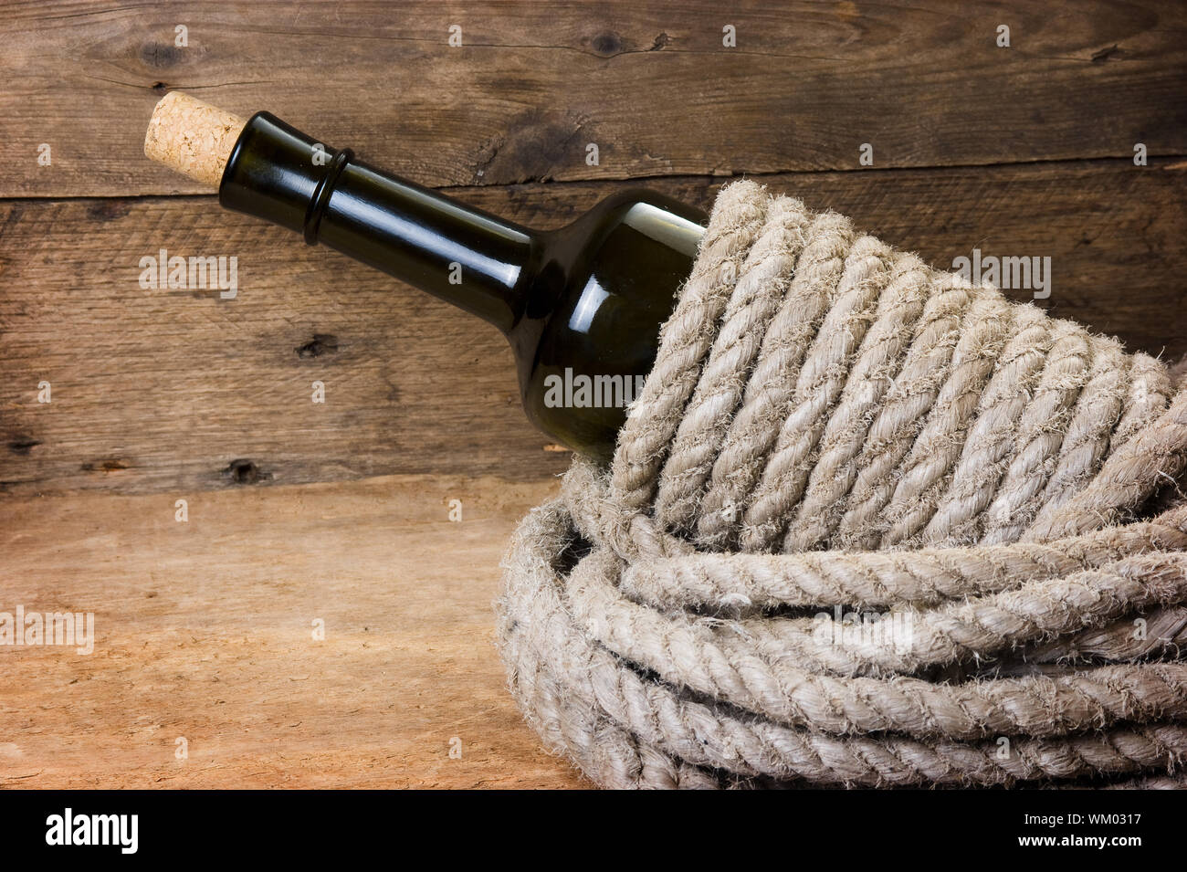 bottle of wine wrapped with rope on the background of the old wooden ...