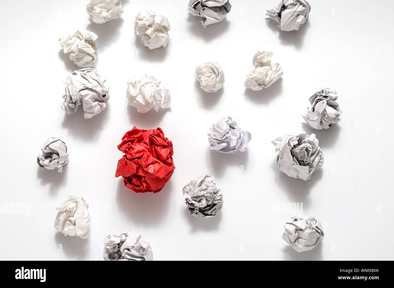 white crumpled paper ball and different red crumpled paper ball on a ...