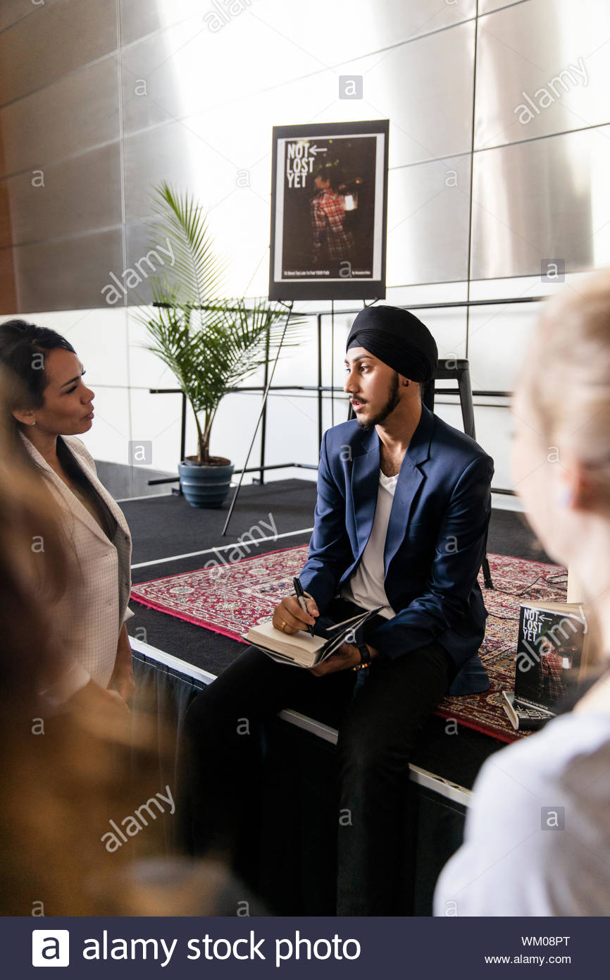 Male author signing books for audience at book launch Stock Photo - Alamy