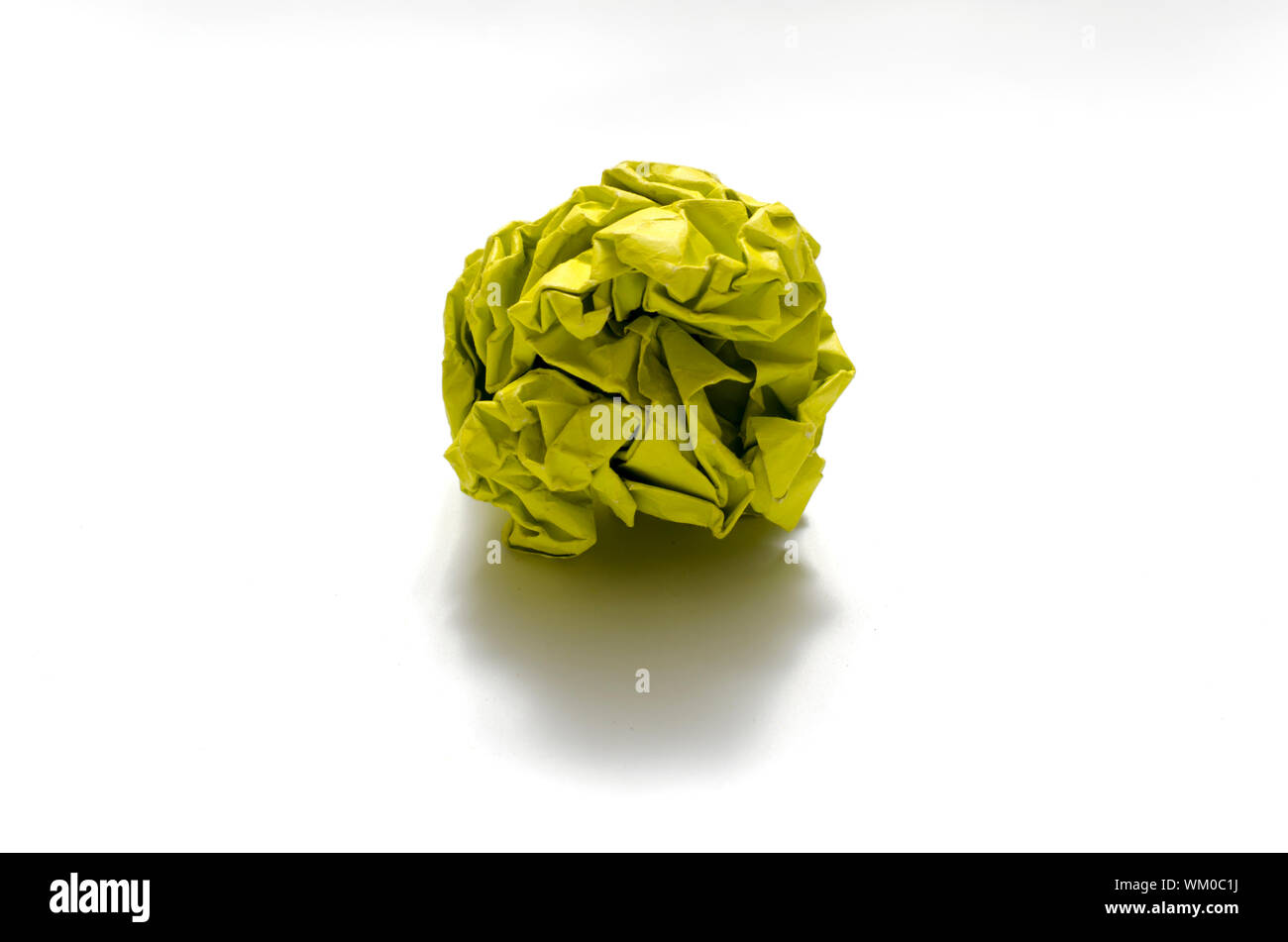 yellow color crumpled paper ball on a white background Stock Photo - Alamy