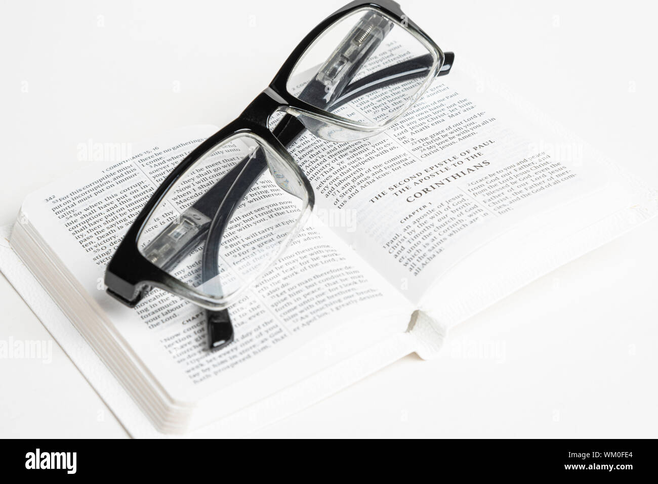 An open white portable pocket bible with a pair of clear reading ...