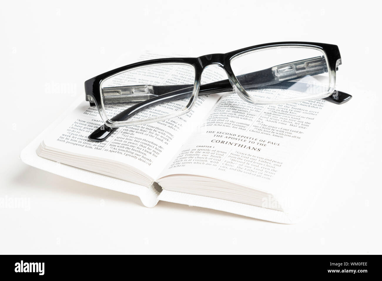 An open white portable pocket bible with a pair of clear reading ...