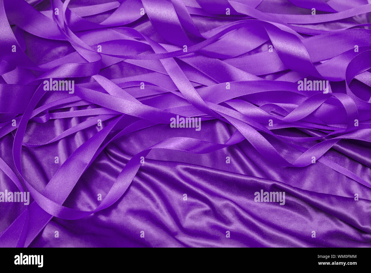purple satin ribbons in a messy mess texture background Stock Photo - Alamy