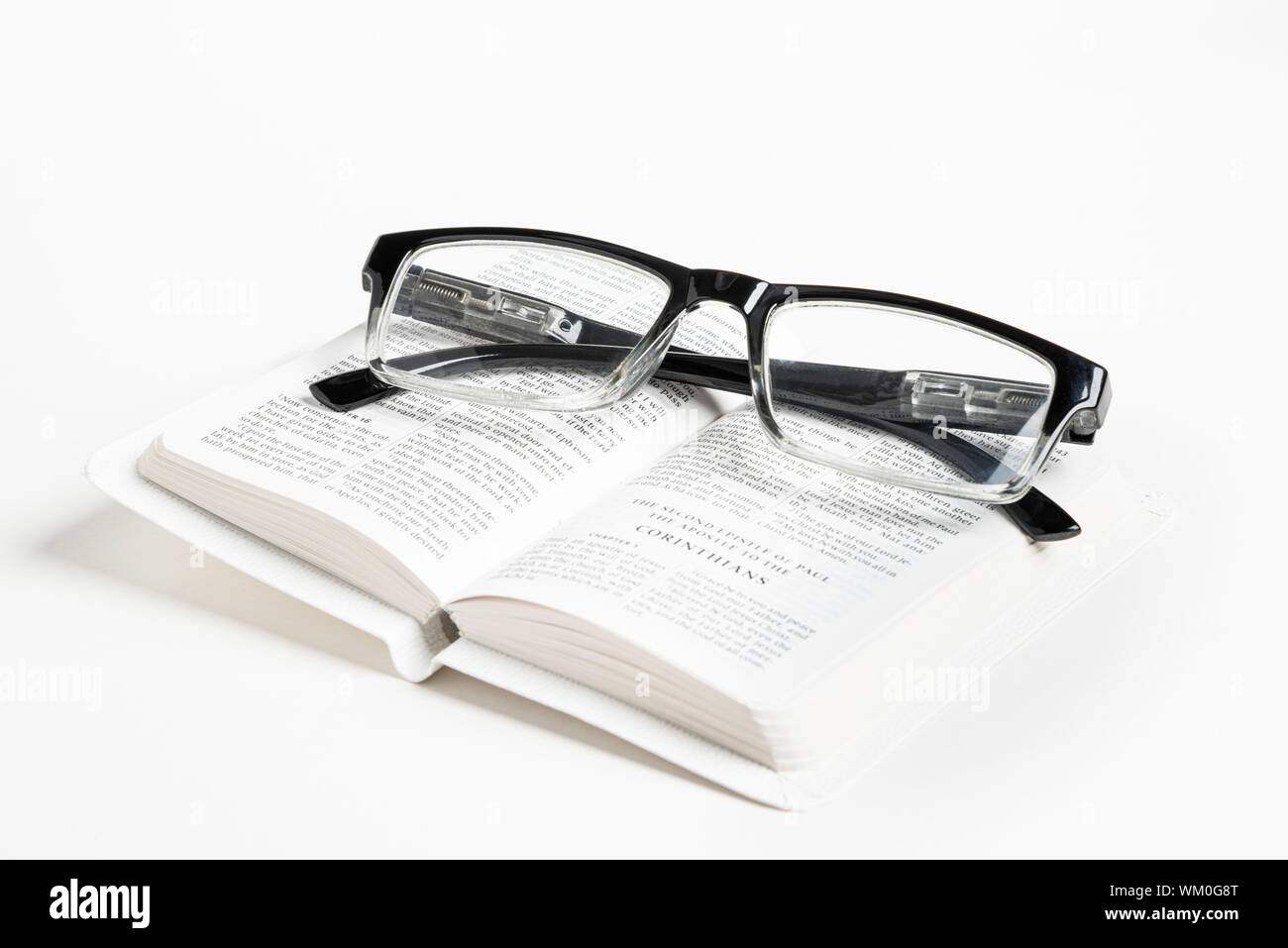 An open white portable pocket bible with a pair of clear reading ...