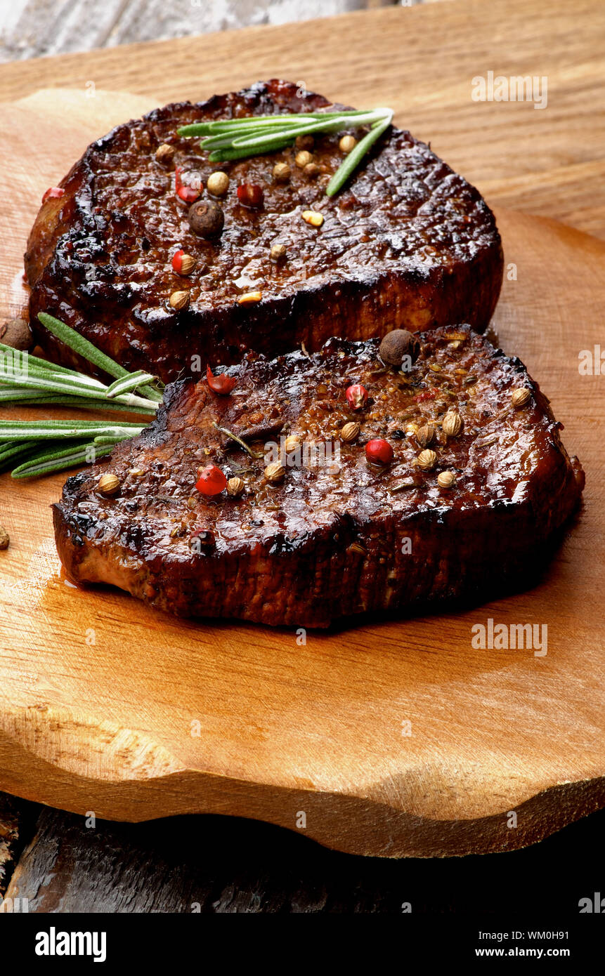Gourmet Roasted Beef Steaks with Spices and Rosemary on Wooden Plate on ...